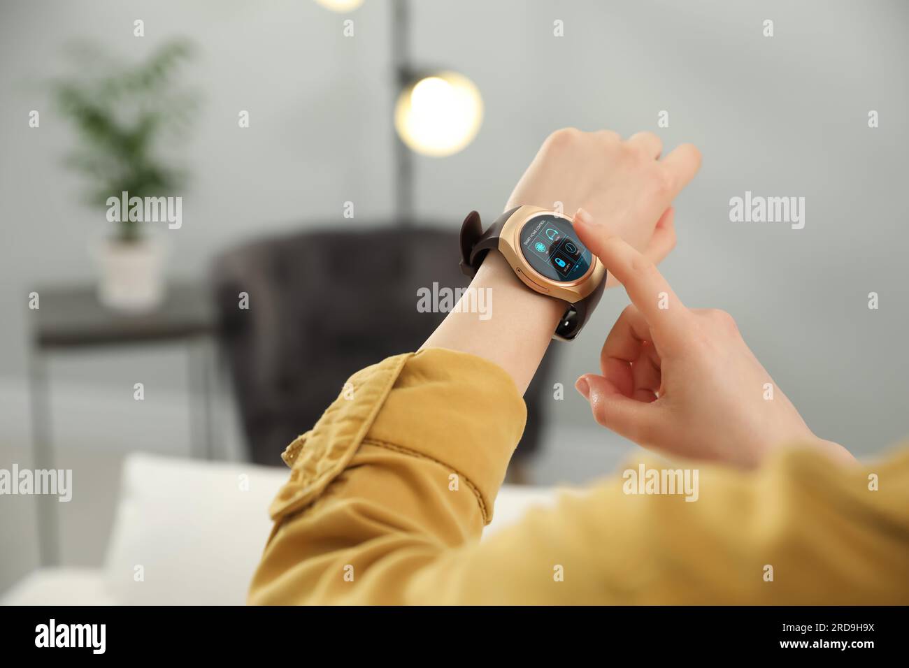 Woman setting smart home control system via smartwatch indoors, closeup ...