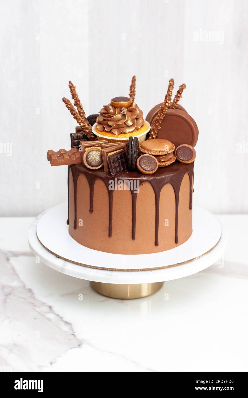Chocolate cake richly decorated with assorted sweets, cupcake, cookies ...