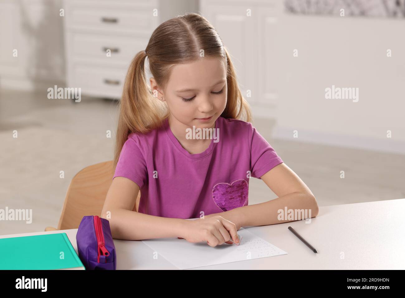 Girl using eraser at white desk in room Stock Photo - Alamy