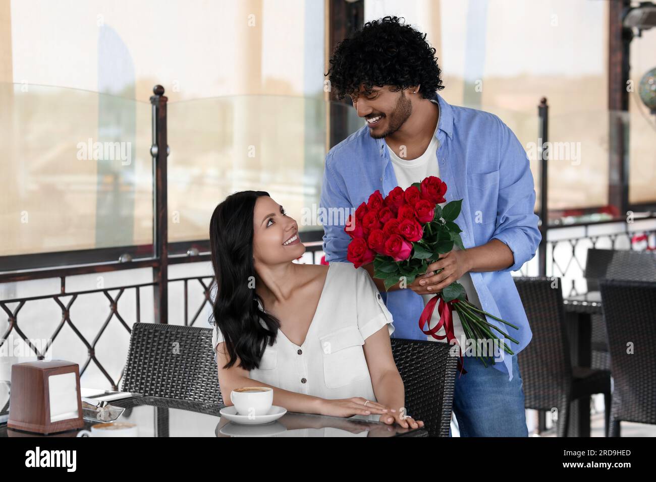 International dating. Handsome man presenting roses to his girlfriend ...