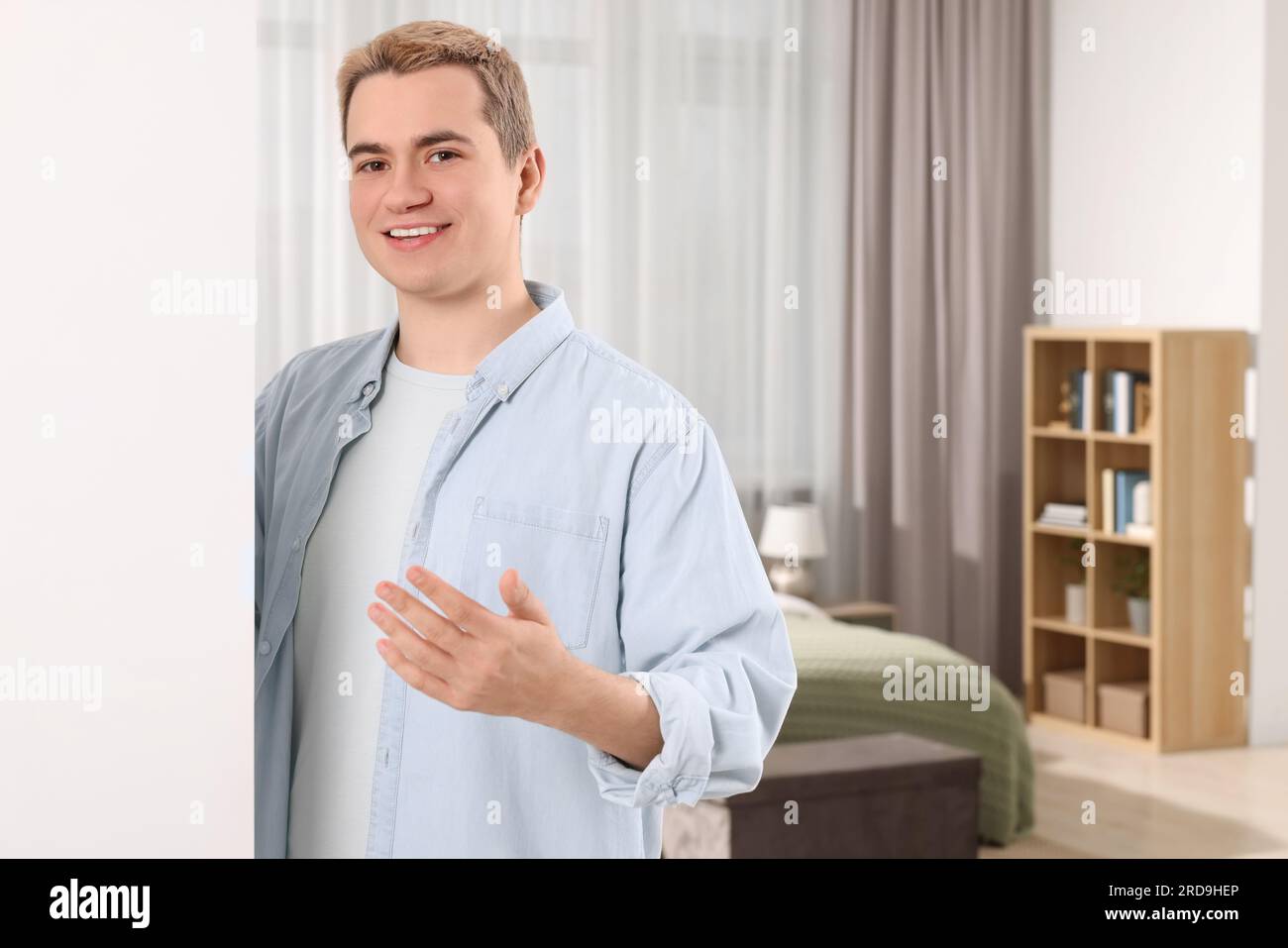 Happy man inviting to come in room Stock Photo - Alamy