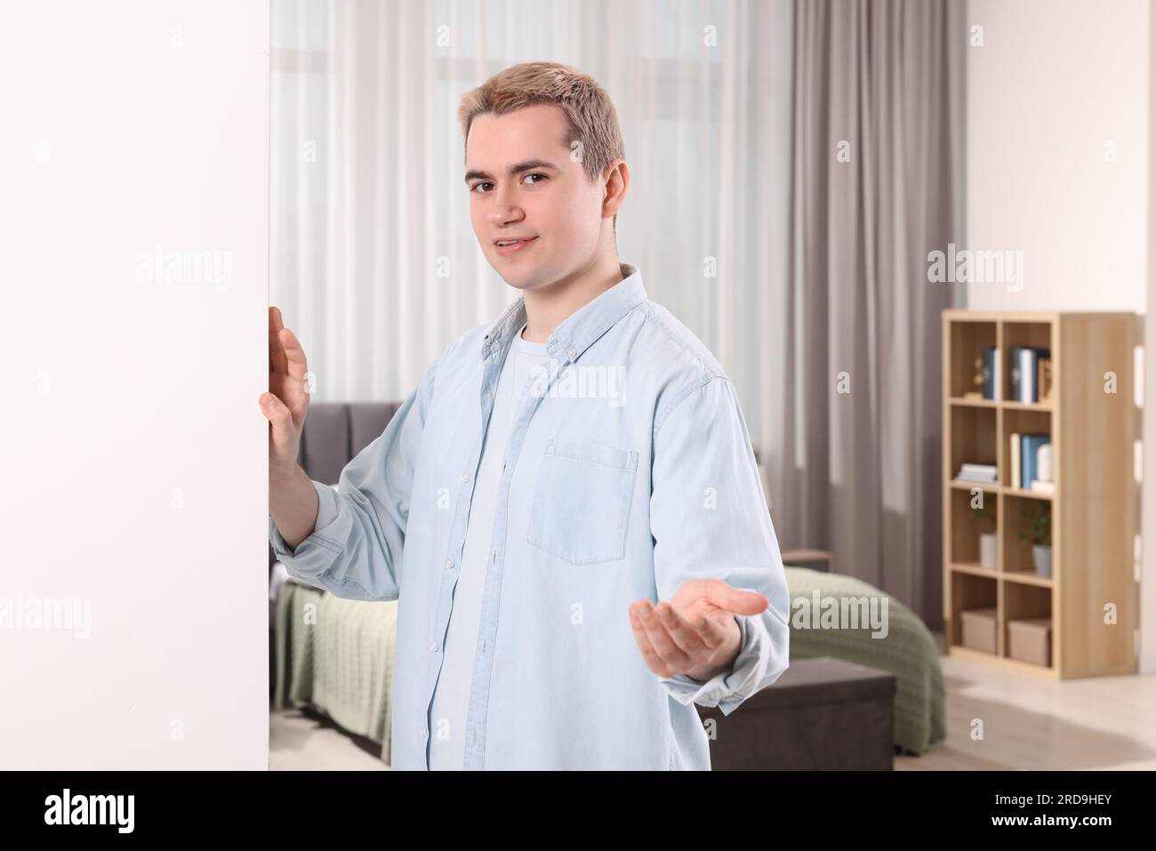 Happy man inviting to come in room Stock Photo - Alamy