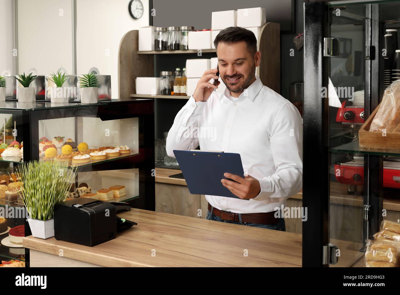 Business owner in his cafe. Man with clipboard talking on phone near ...