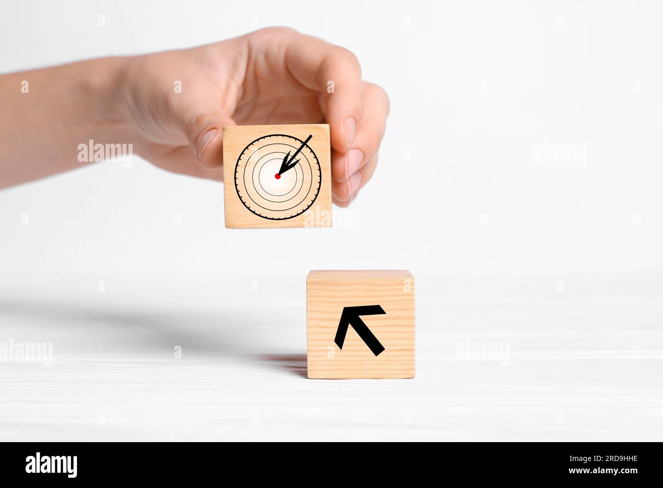 Woman putting cube with icon of target on white background, closeup ...