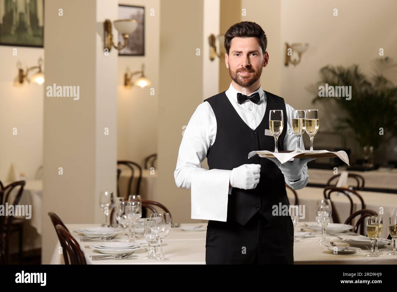 Butler holding tray with glasses of sparkling wine in restaurant. Space ...