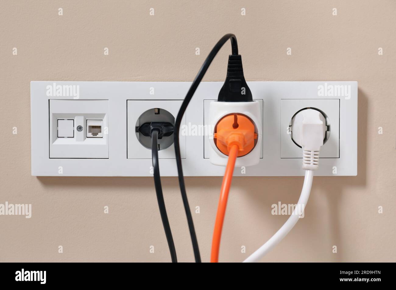 Many different electrical power plugs in sockets on beige wall Stock ...