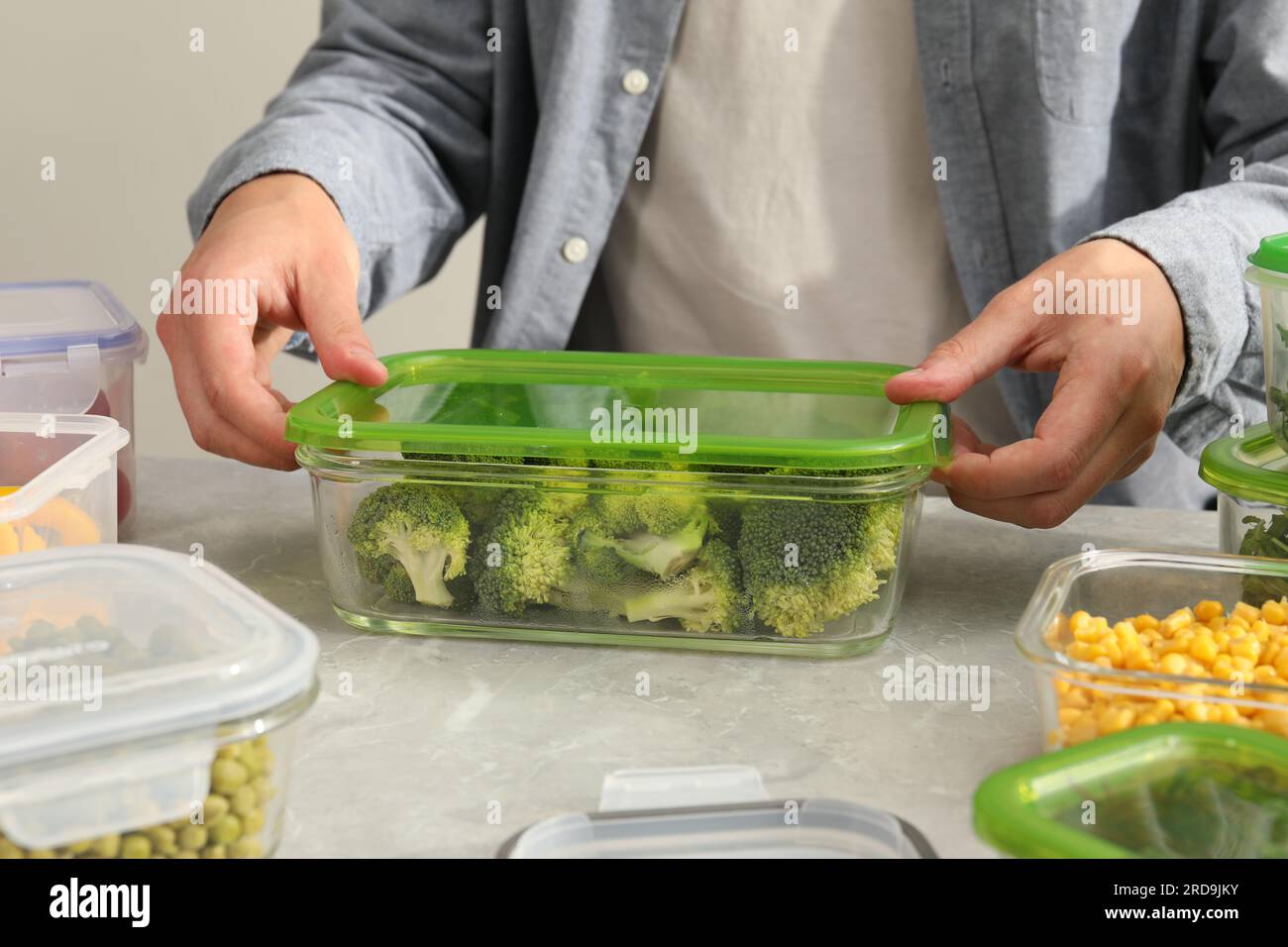 Man closing glass container with lid at light grey marble table in ...
