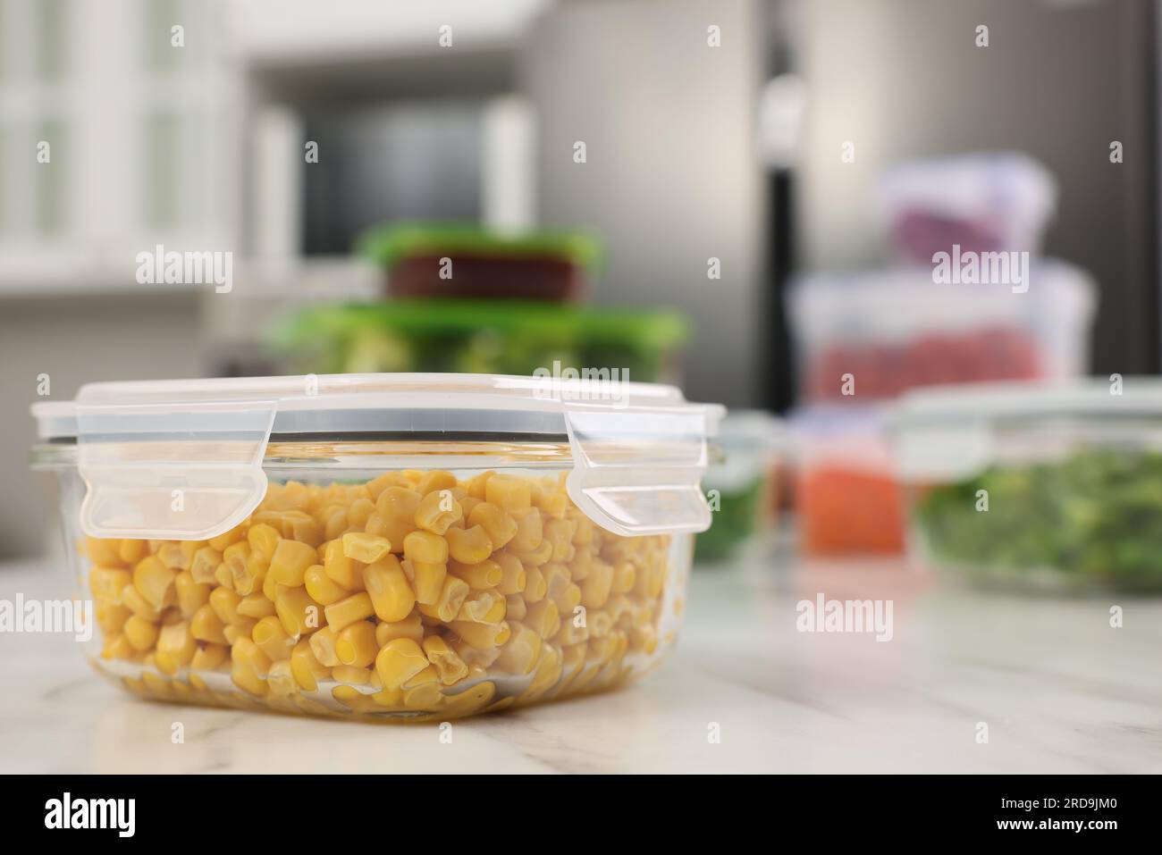 Glass container with tasty corn kernels on white marble table in ...