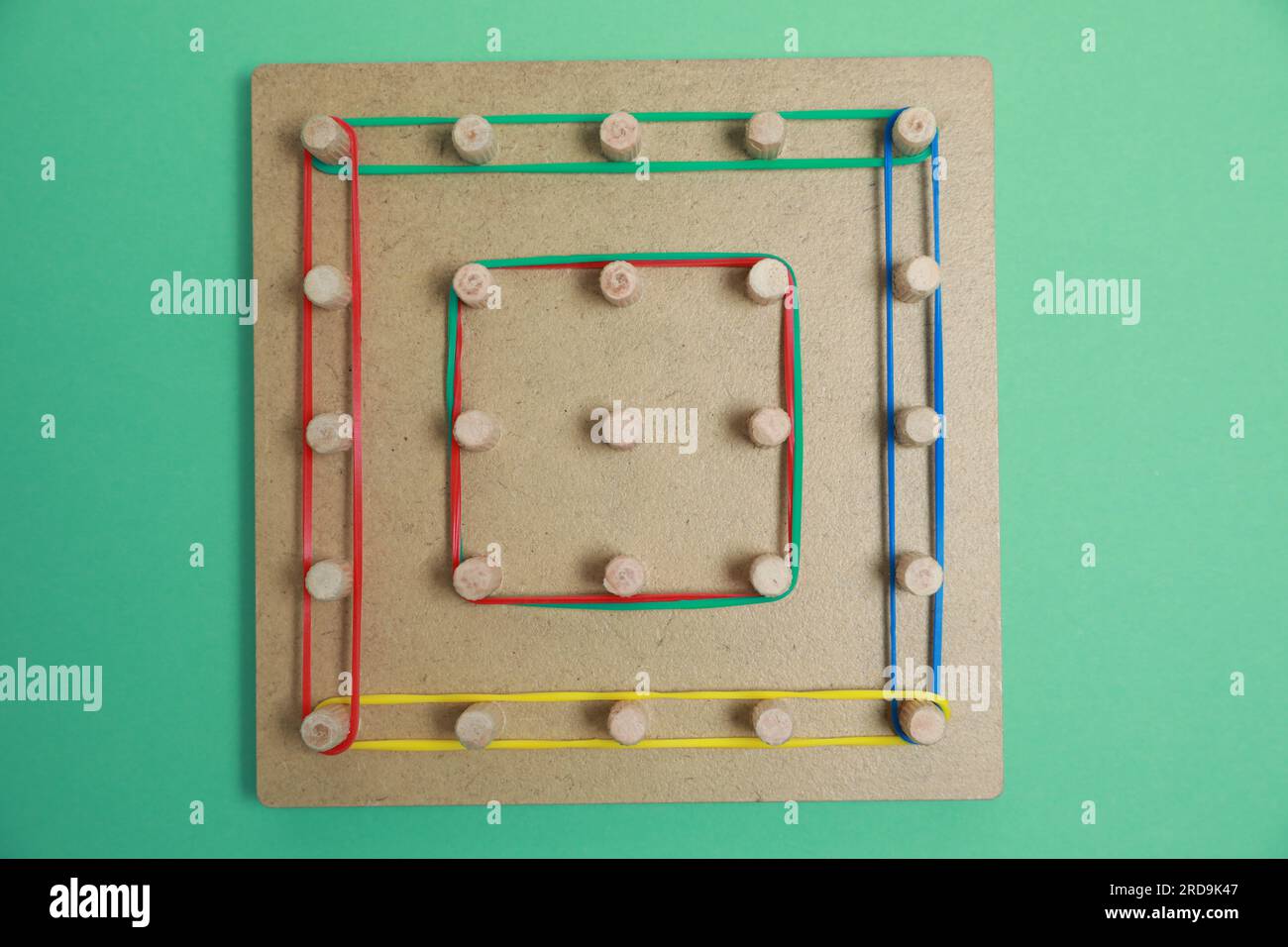 Wooden geoboard with rubber bands on green background, top view ...