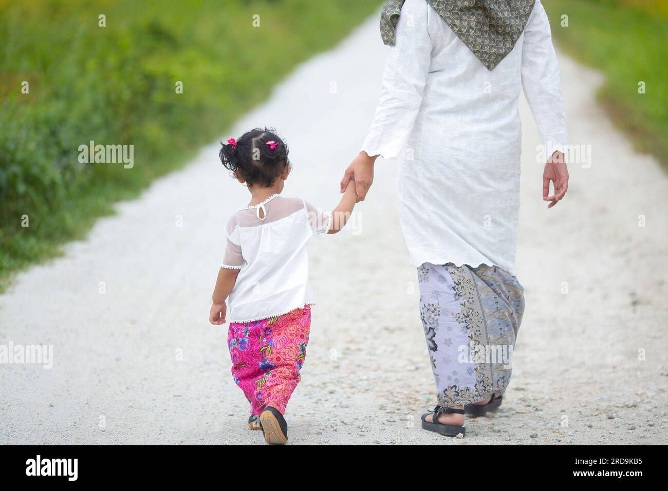 Mom holding her baby girl hand with hari raya dress Stock Photo - Alamy