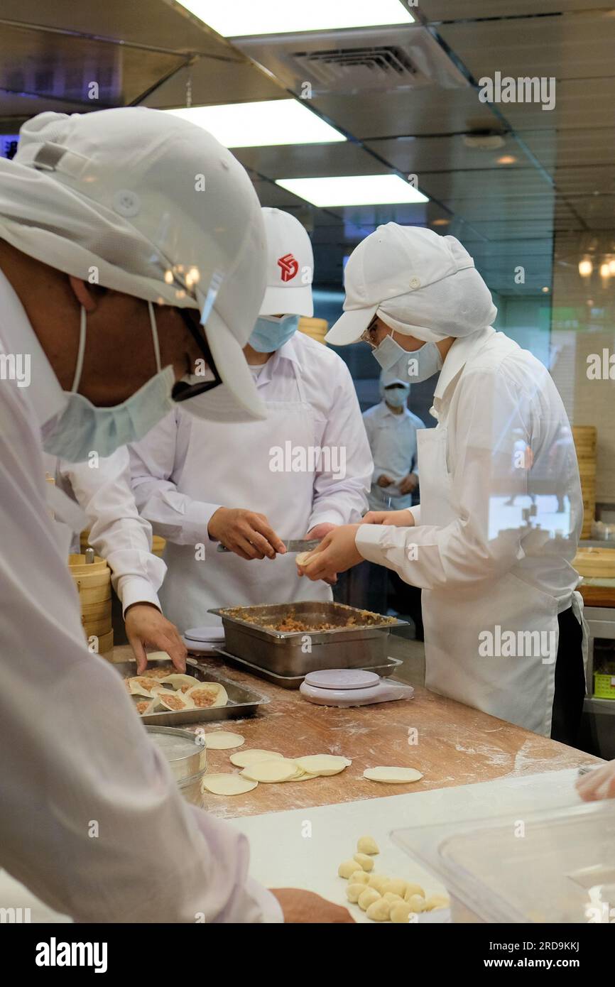Cooks and kitchen staff making dumplings, bao, and other Chinese dim ...