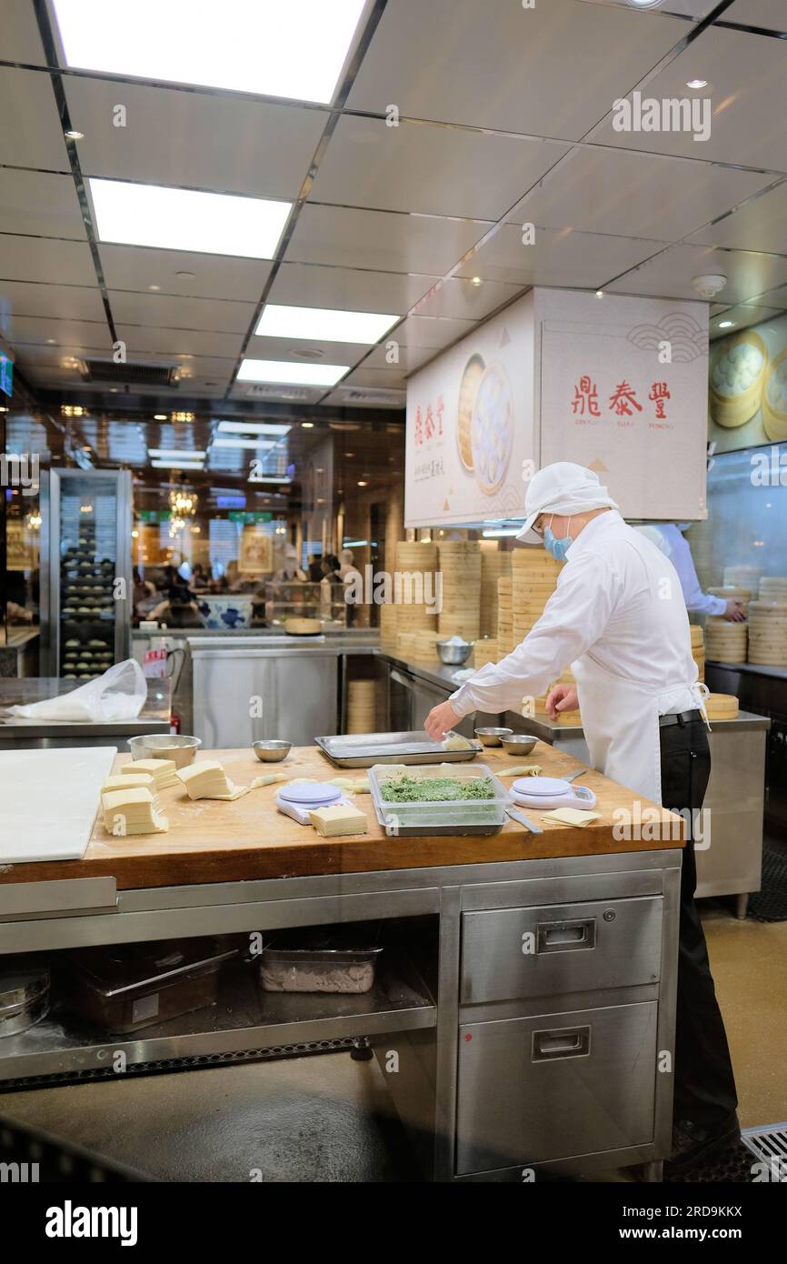 Cooks and kitchen staff making dumplings, bao, and other Chinese dim ...