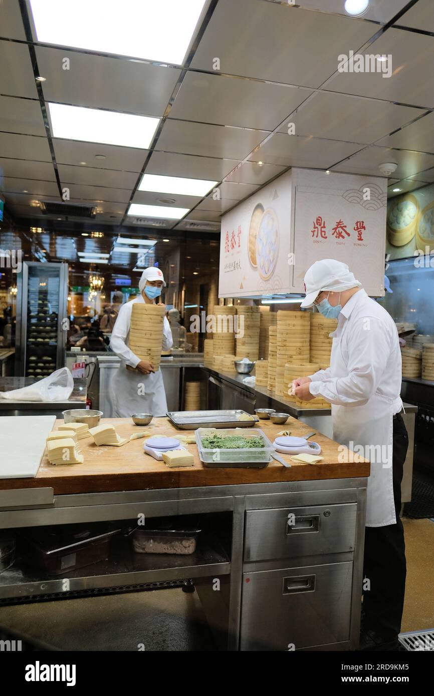Cooks and kitchen staff making dumplings, bao, and other Chinese dim ...