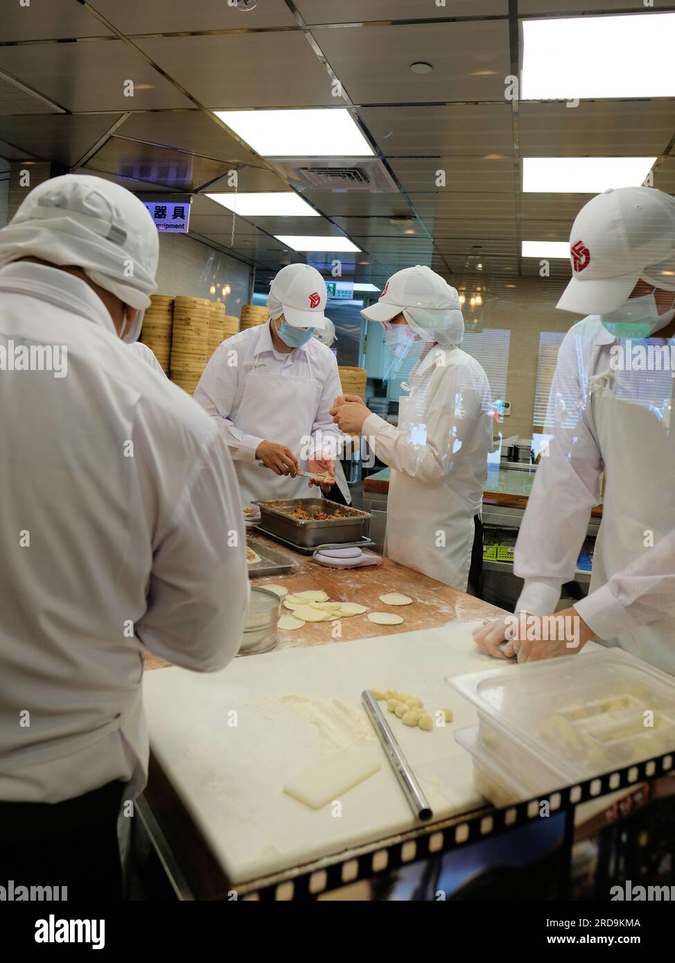 Cooks and kitchen staff making dumplings, bao, and other Chinese dim ...