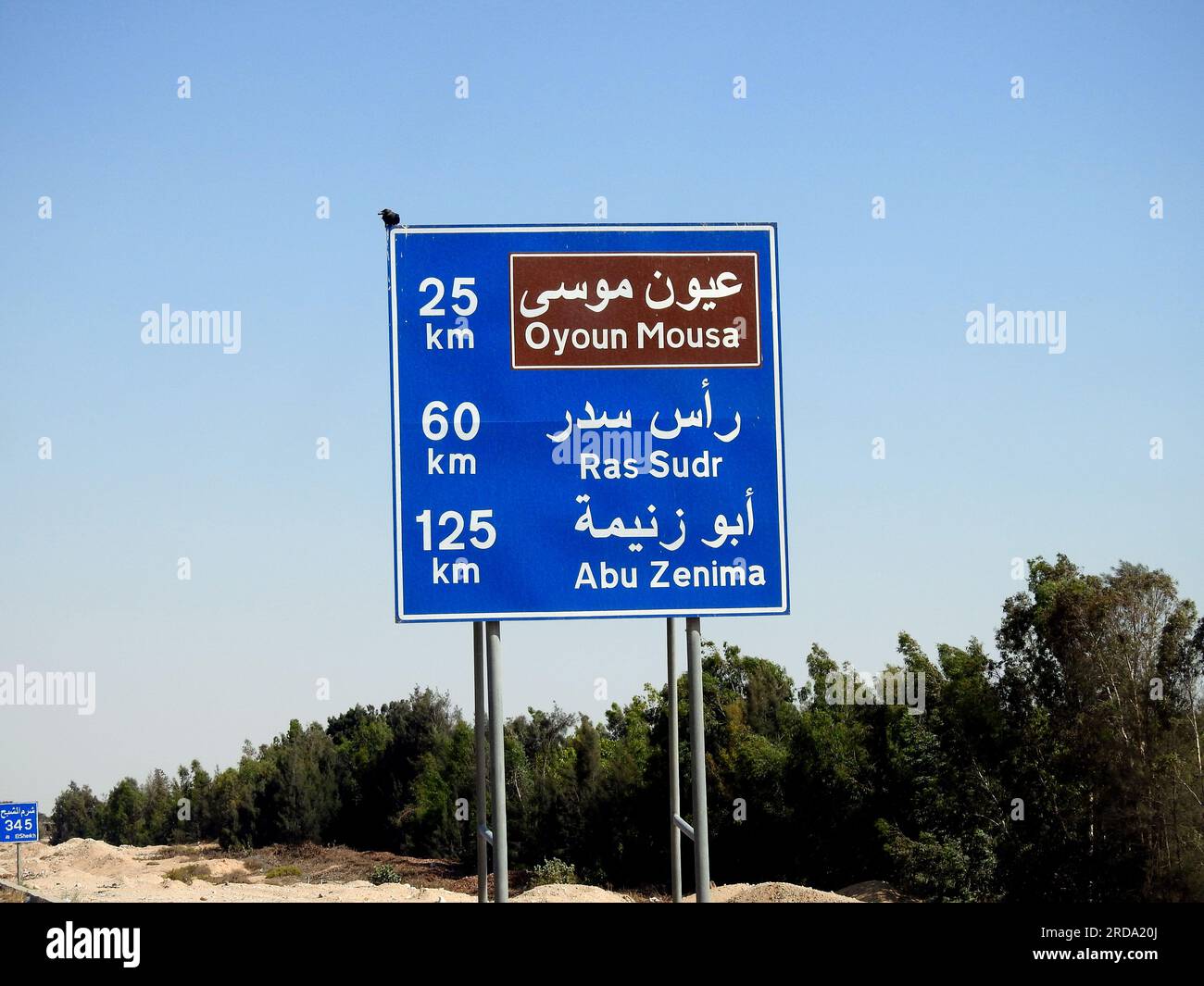 A road traffic board sign in Arabic and English shows the distance to ...
