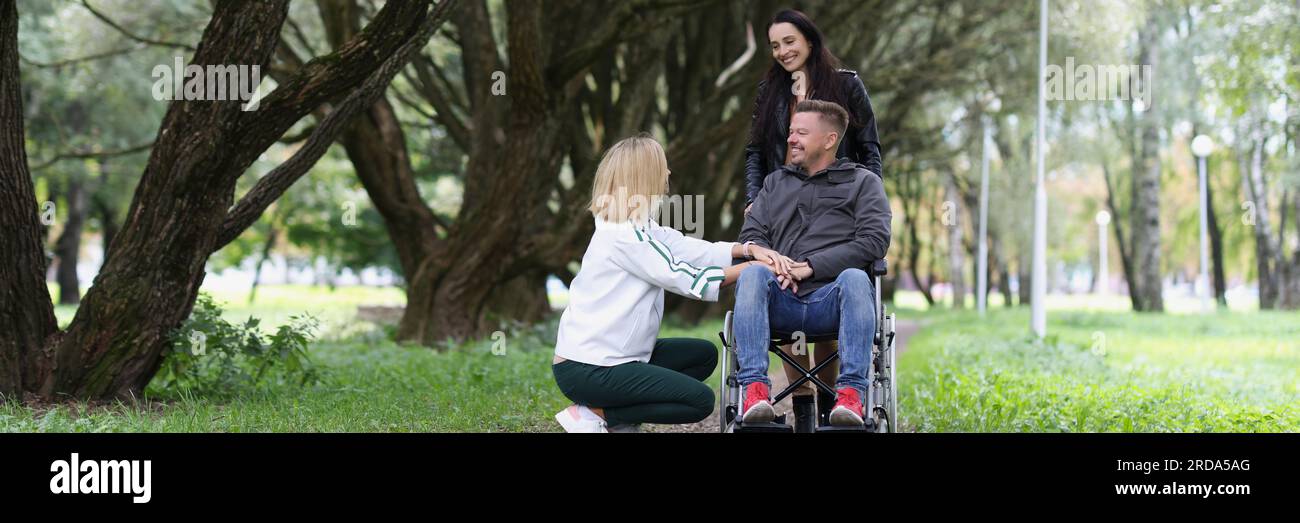 Happy disabled person in wheelchair and two women take care of him in ...