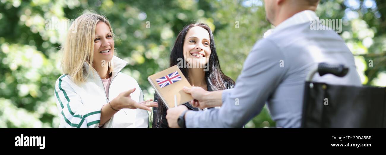 Three friends talk and study outdoors, one disabled person in ...
