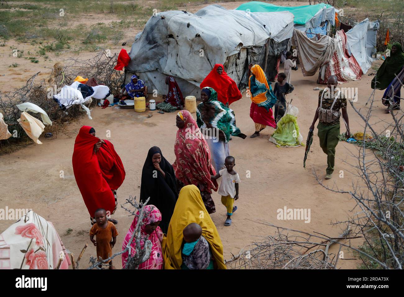 Somali refugees and an armed Kenyan policeman walk next to a makeshift ...