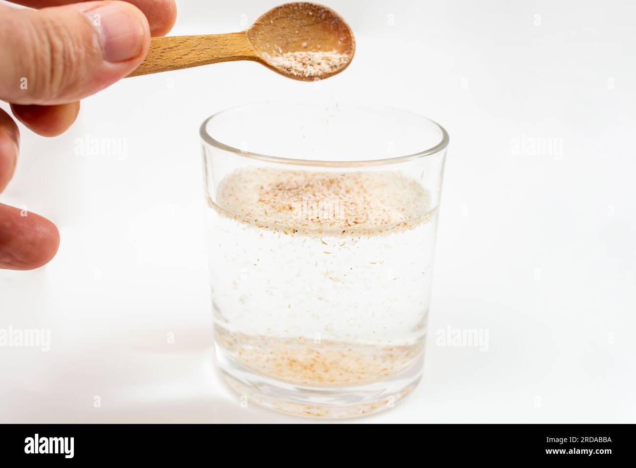 Hand mixing a tea spoon full of psyllium husk with water in a ...