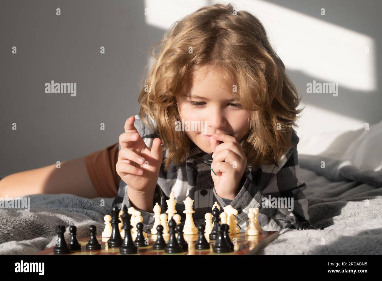 Little kid play chess. Thinking child. Chess game with children at home ...