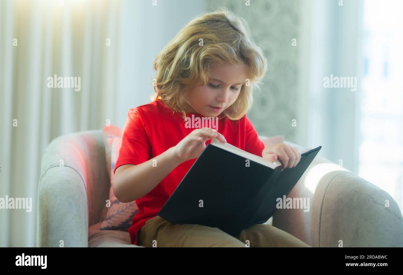 Child reading book at home. Little boy sitting on couch in living room ...