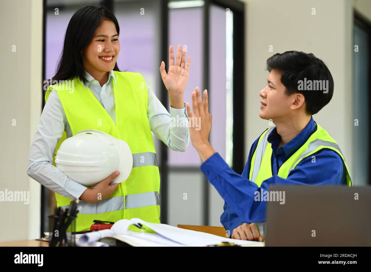 Smiling asian female engineer giving high five with colleague ...