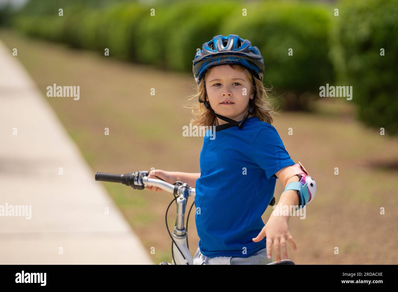 Child riding bicycle. Little kid boy in helmet on bicycle along bikeway ...