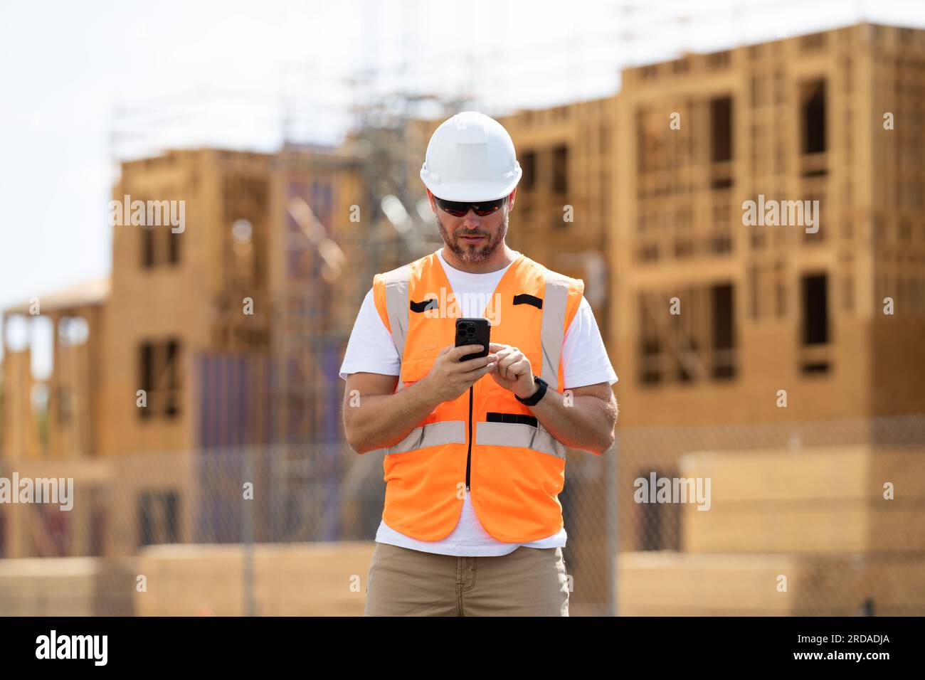 Worker man on the building construction. Worker using phone, builder ...