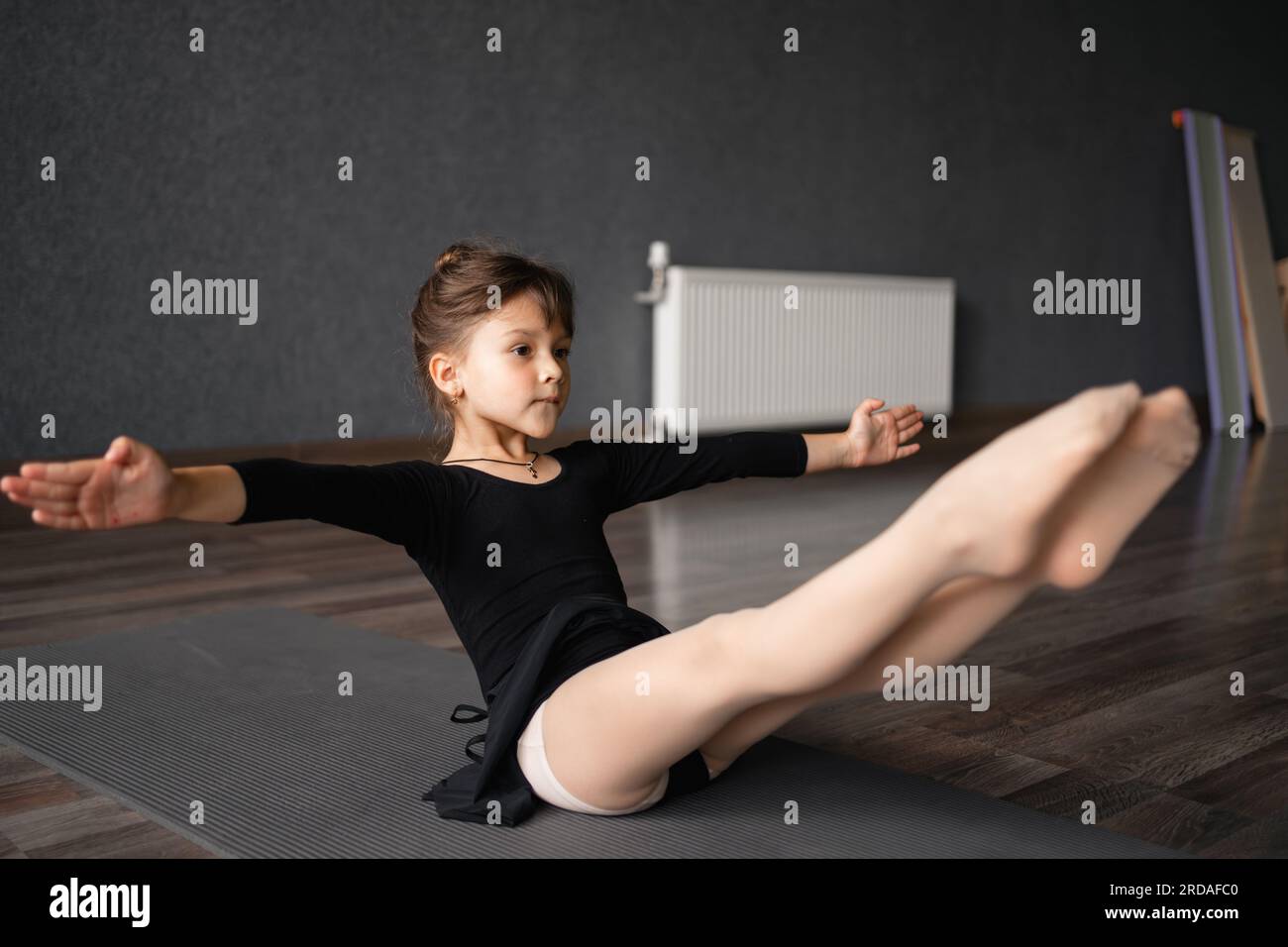 Small child girl doing V-sit exercise for core strength during her ...