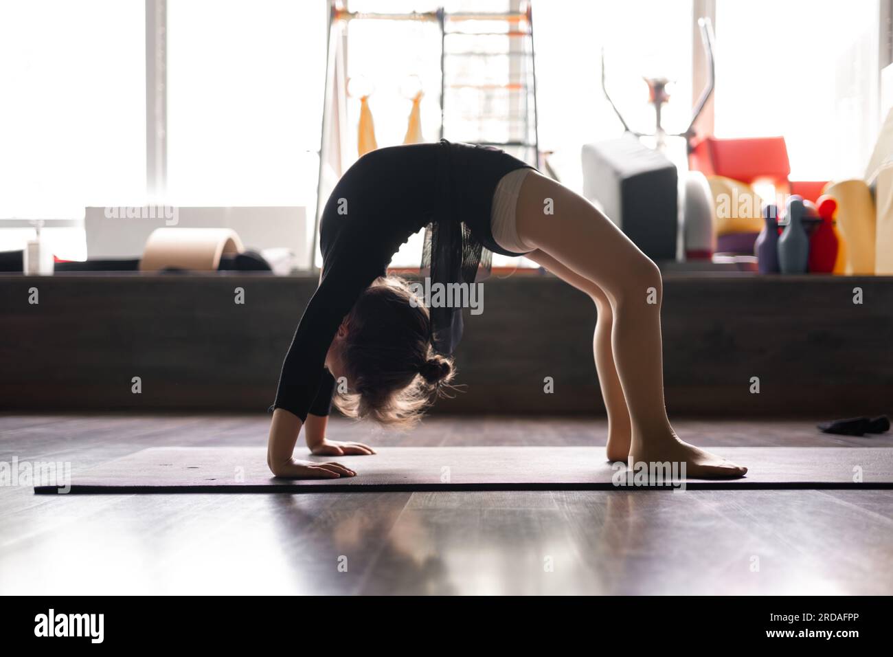 Small girl doing bridge stand exercise in the training studio. Yoga for ...