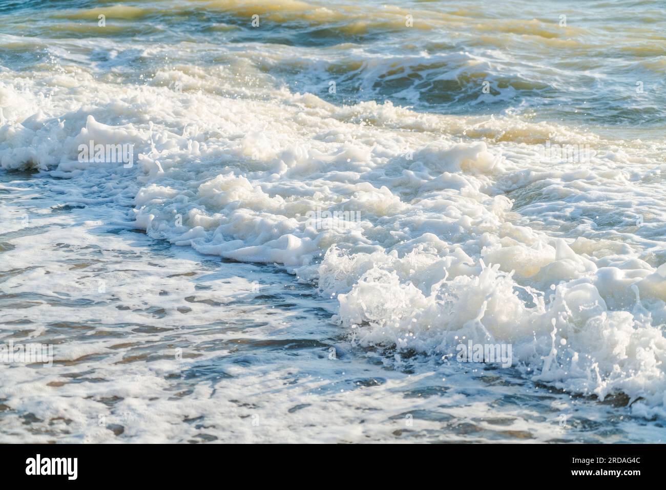 foaming rolling waves on the sandy shore Stock Photo - Alamy