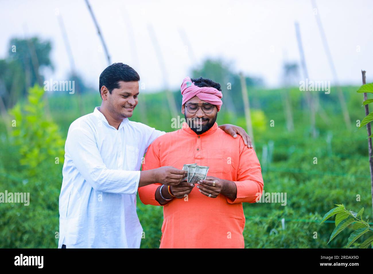 Indian farmer giving money to his worker , smart farmer, young farmer ...