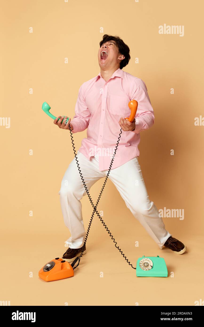 Too many tasks. Young emotional man talking on two phones at same time ...