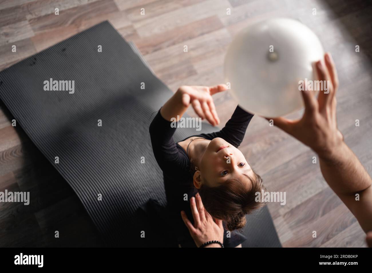 Smal child girl doing stretching exercises with coach on the sport mat ...