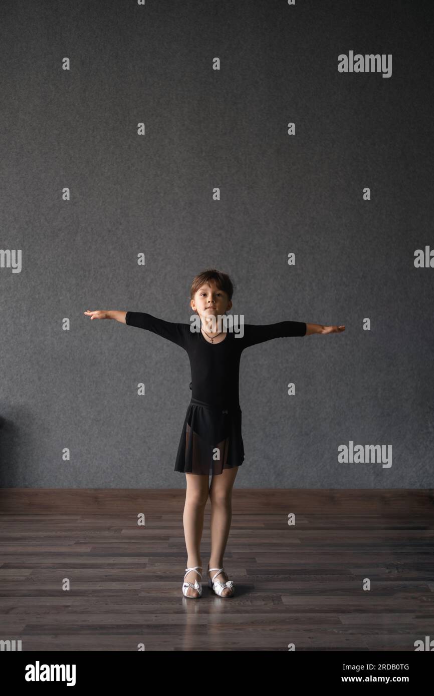 Child girl standing in black sport bodysuit in dancing studio during ...