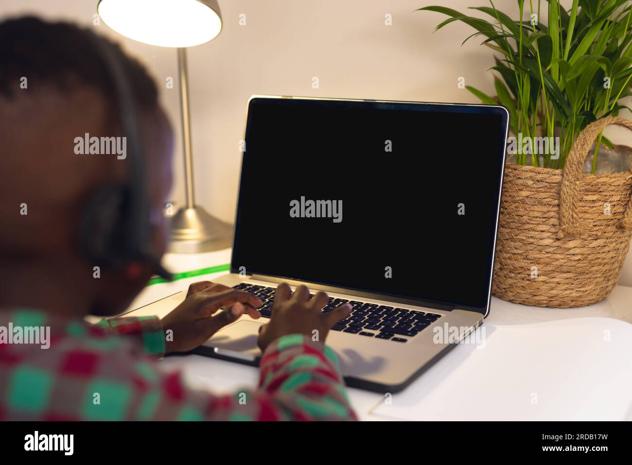 African american boy in headphones typing on laptop keyboard while ...
