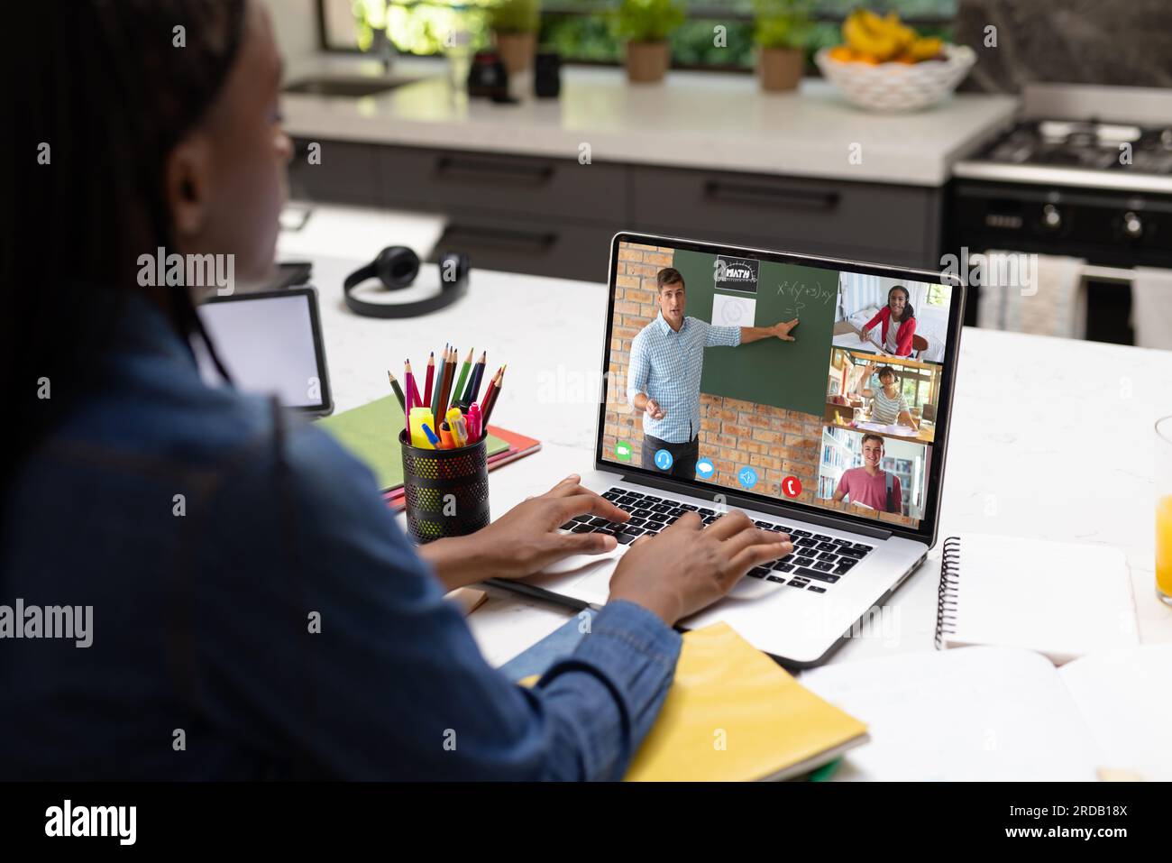 African american teenage boy looking at laptop screen with teacher and ...