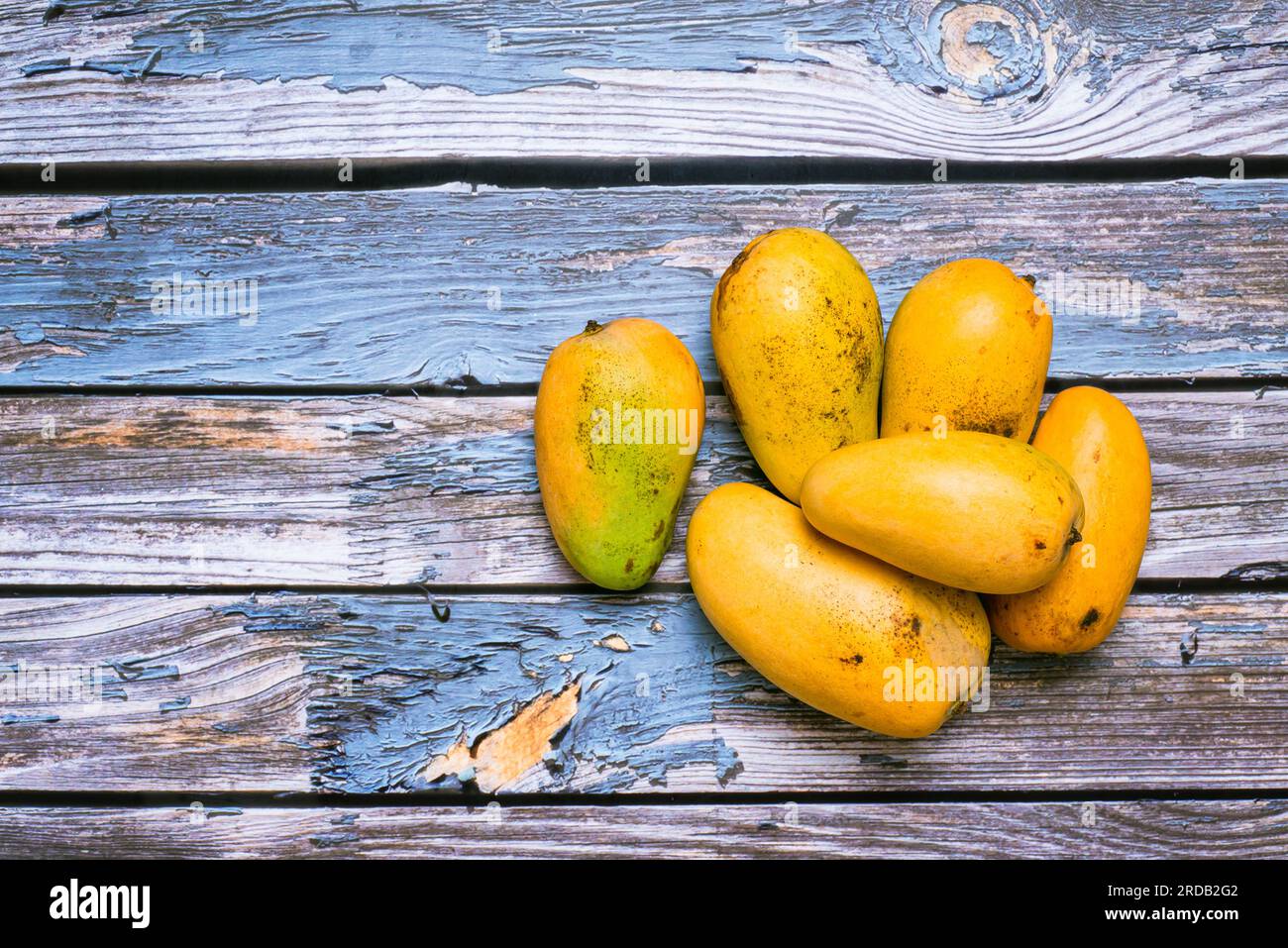 Group of ripe mangoes in dark environment on wooden table. Top view ...