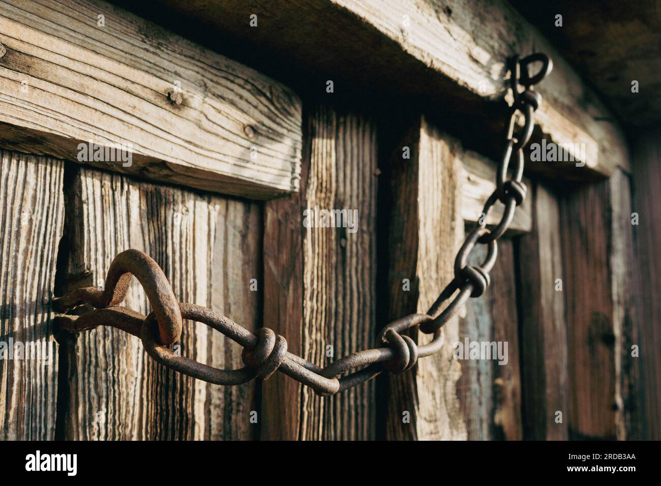 An old vintage textured wooden door with cast iron chain used for lock ...