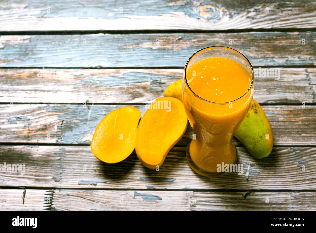 Glass of mango juice and sliced mangoes on wooden table. Colorful scene ...