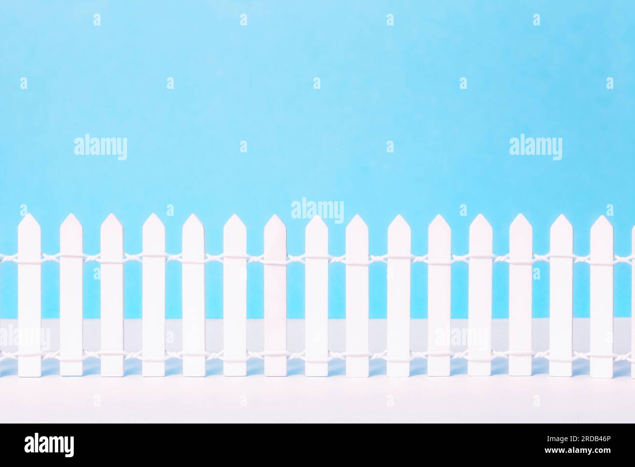 Wooden vintage white picket fence on blue background. Small paint ...