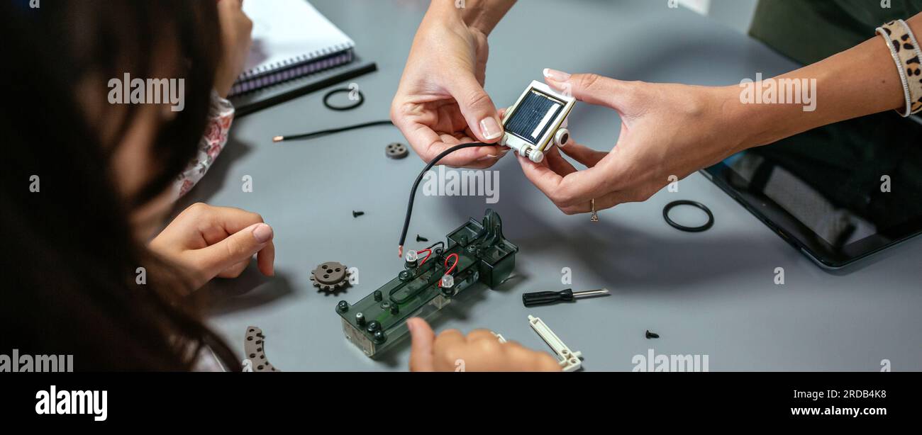 Female teacher explaining to student how connect a solar panel on ...