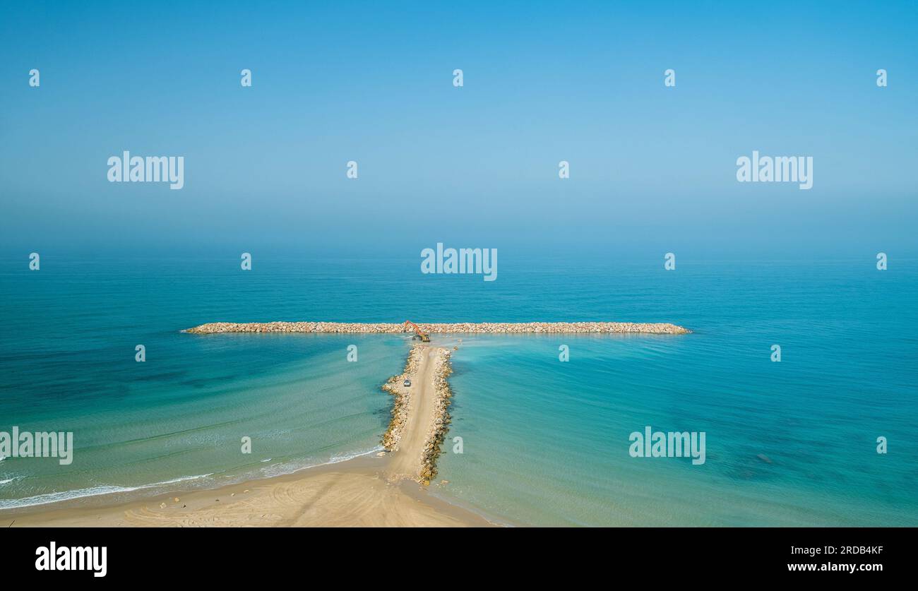 Sea breakwater in the distance, the bay, the beach. Construction of ...