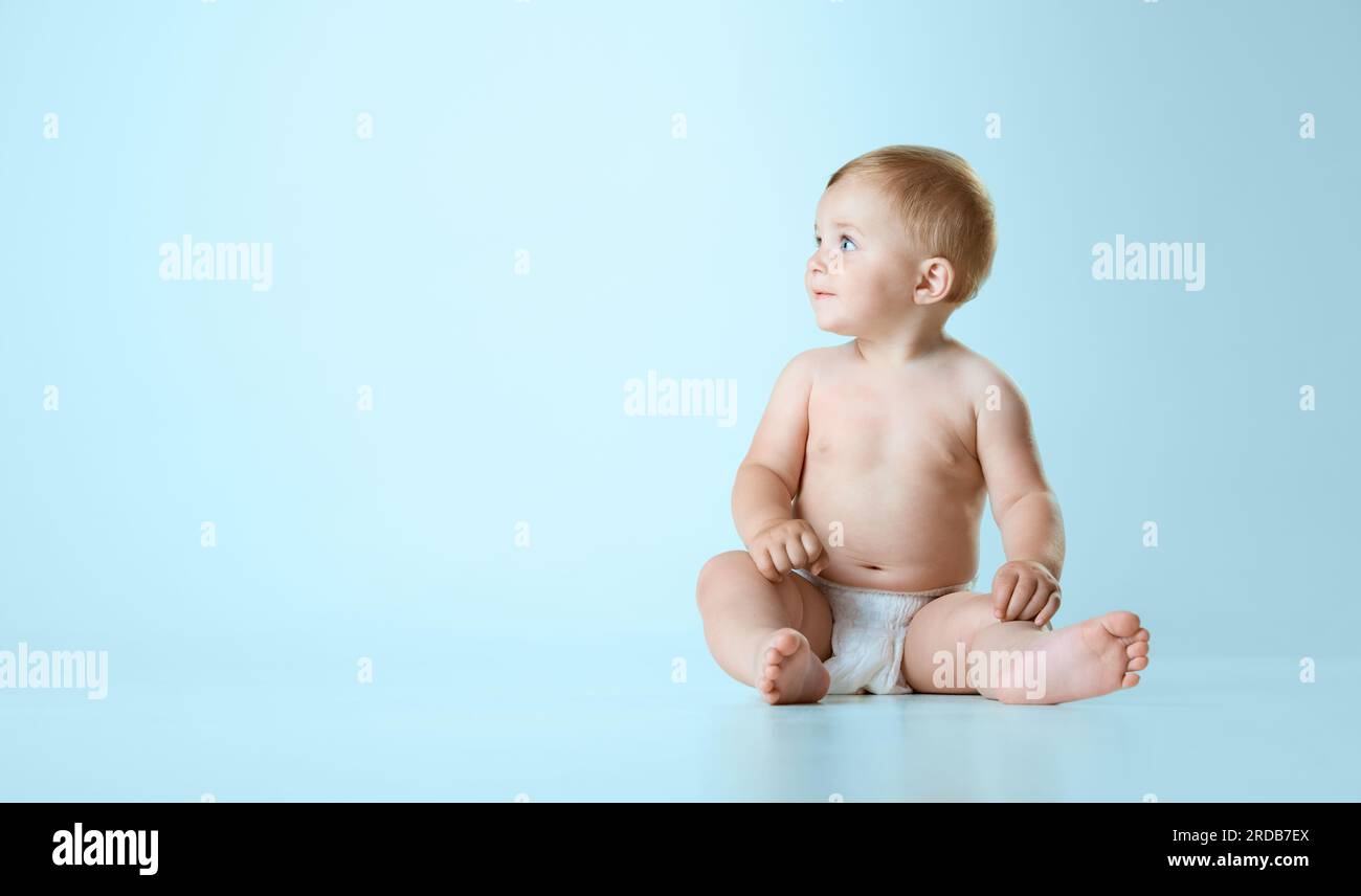 Portrait of beautiful little baby, toddler in diaper sitting calmly on ...