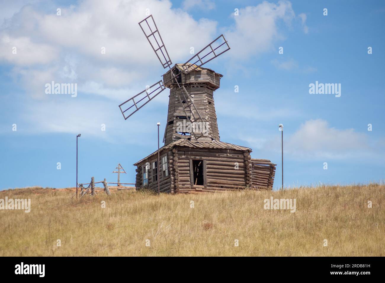 Old partly ruined traditional windmill on hill of yellow grass against ...