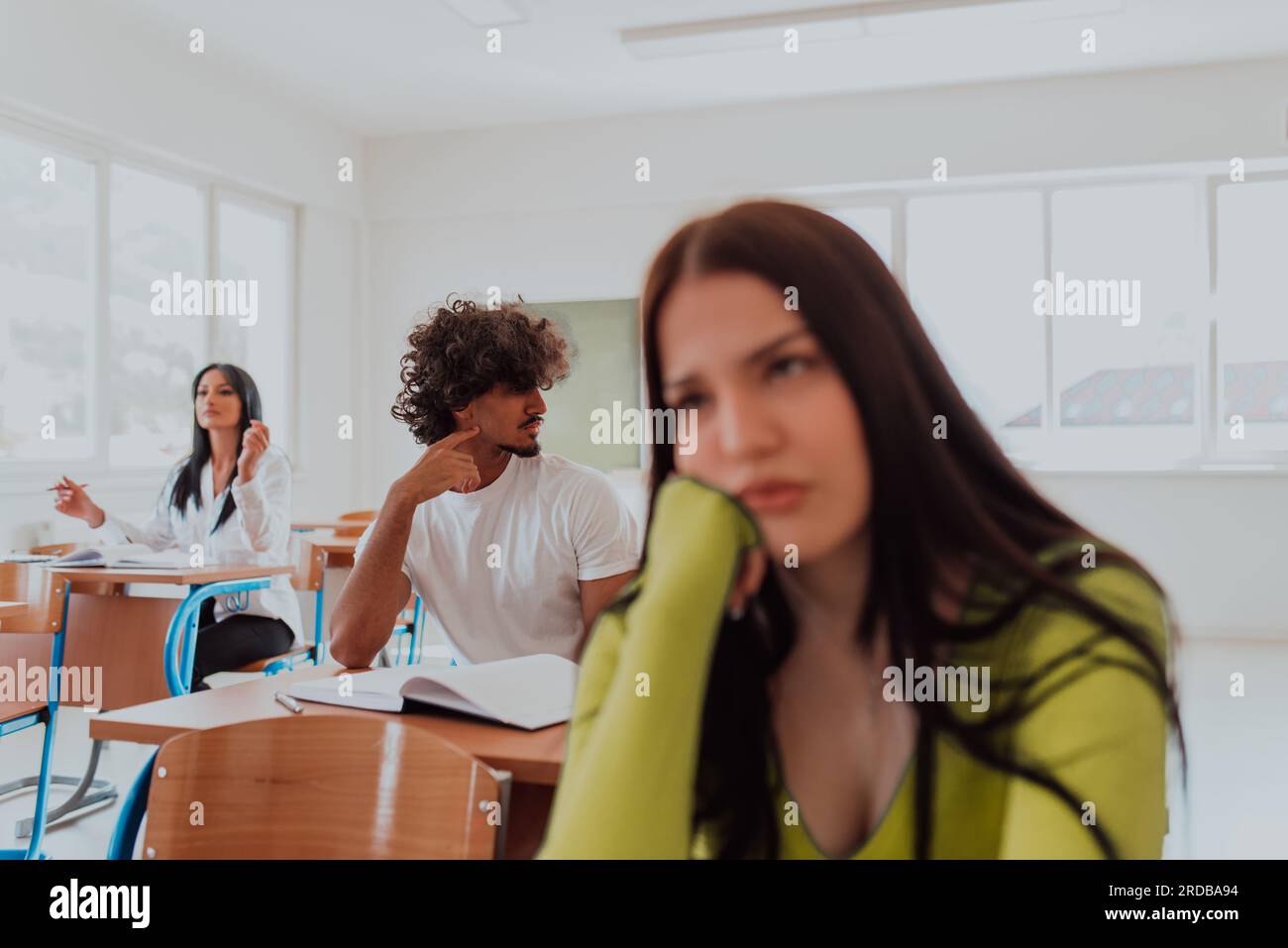 A weary-looking student sitting in front of a group of diverse students ...