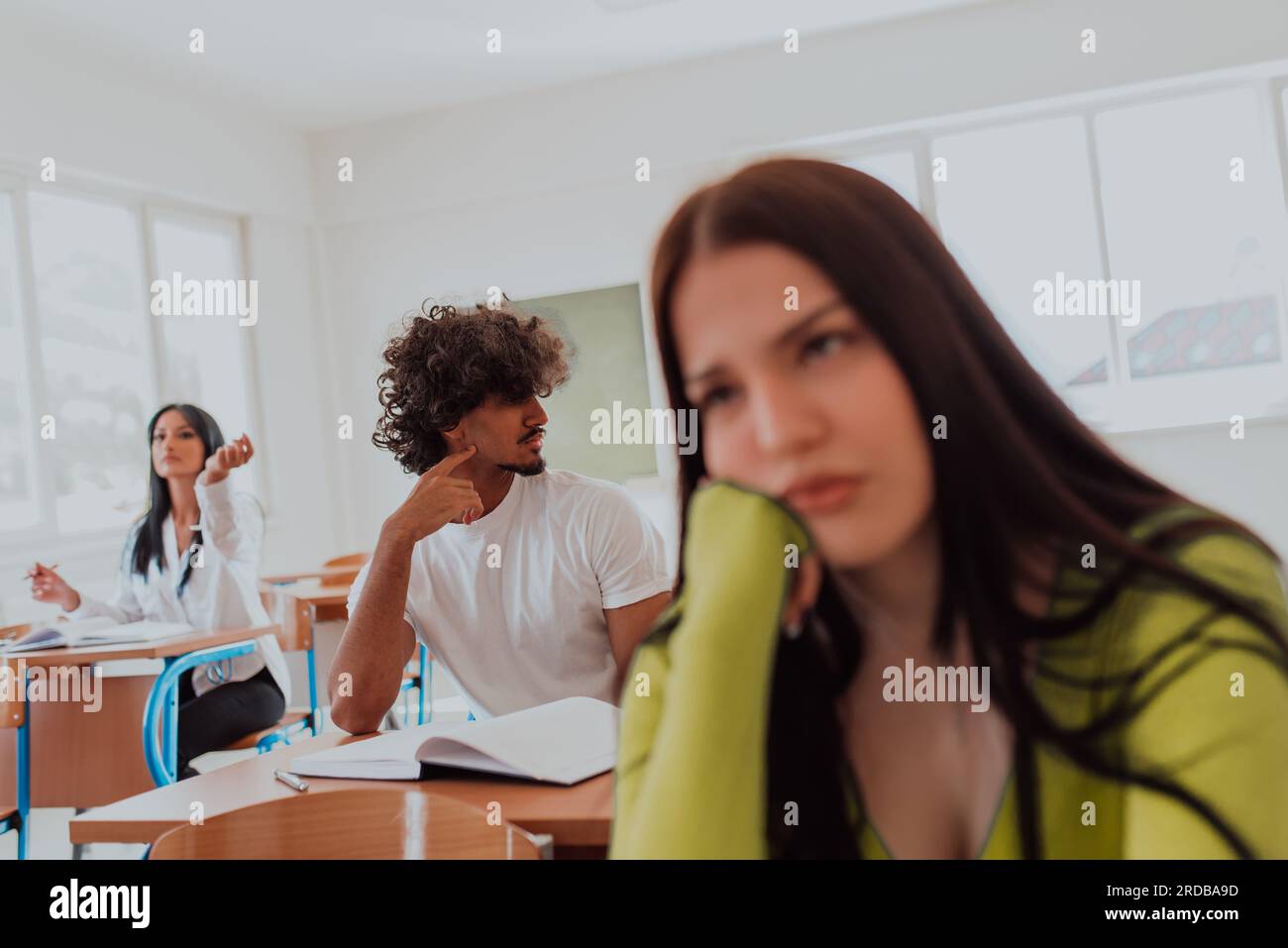 A weary-looking student sitting in front of a group of diverse students ...