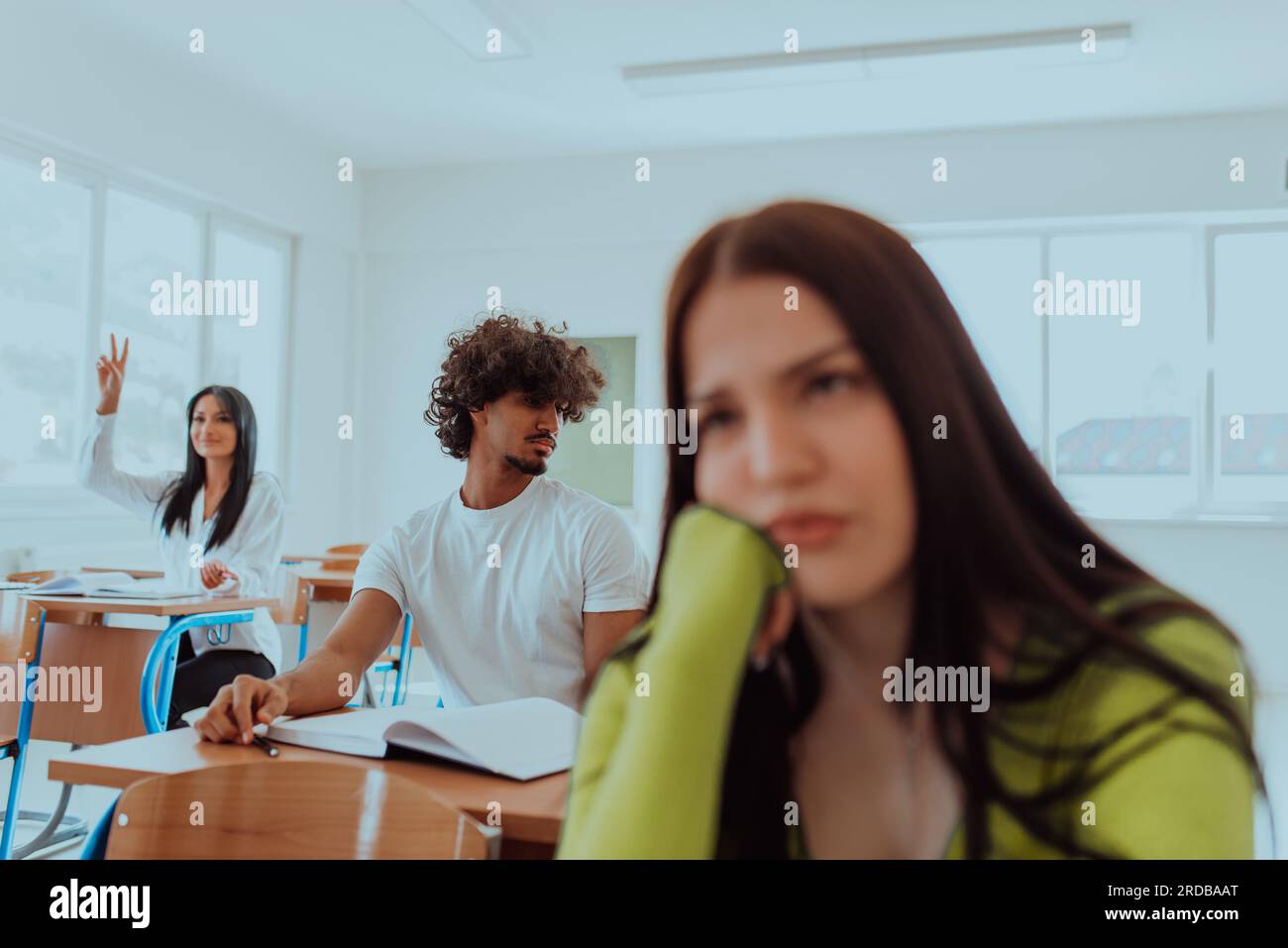 A weary-looking student sitting in front of a group of diverse students ...