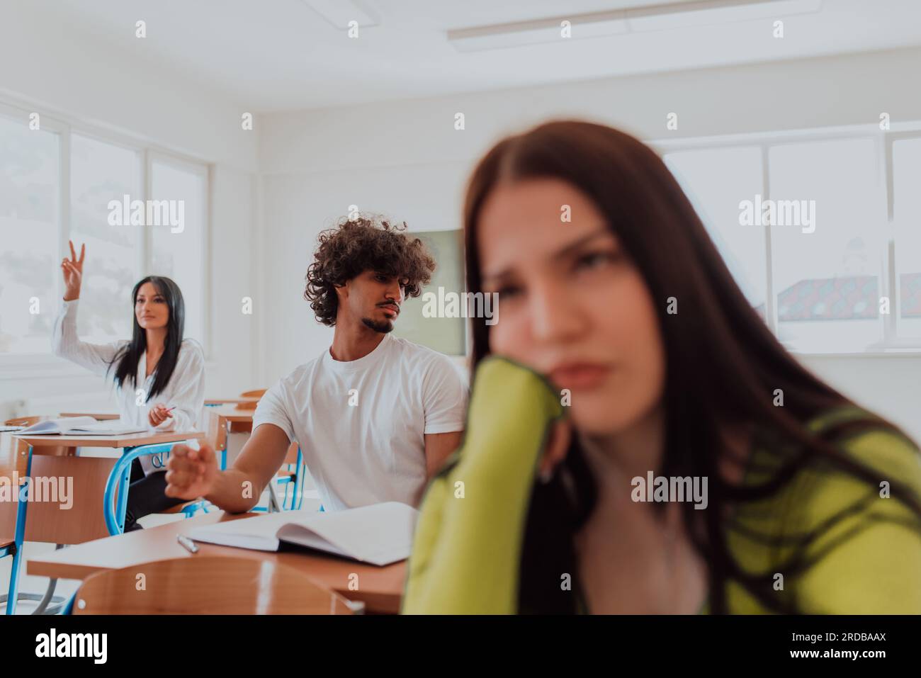 A weary-looking student sitting in front of a group of diverse students ...