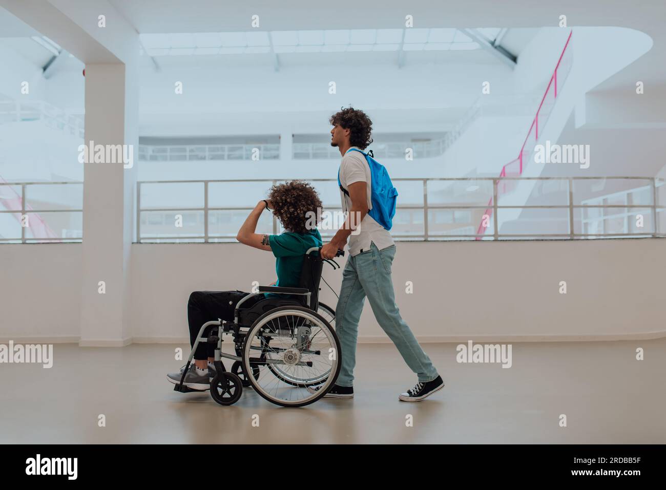 African American student pushing his friend's wheelchair through a ...